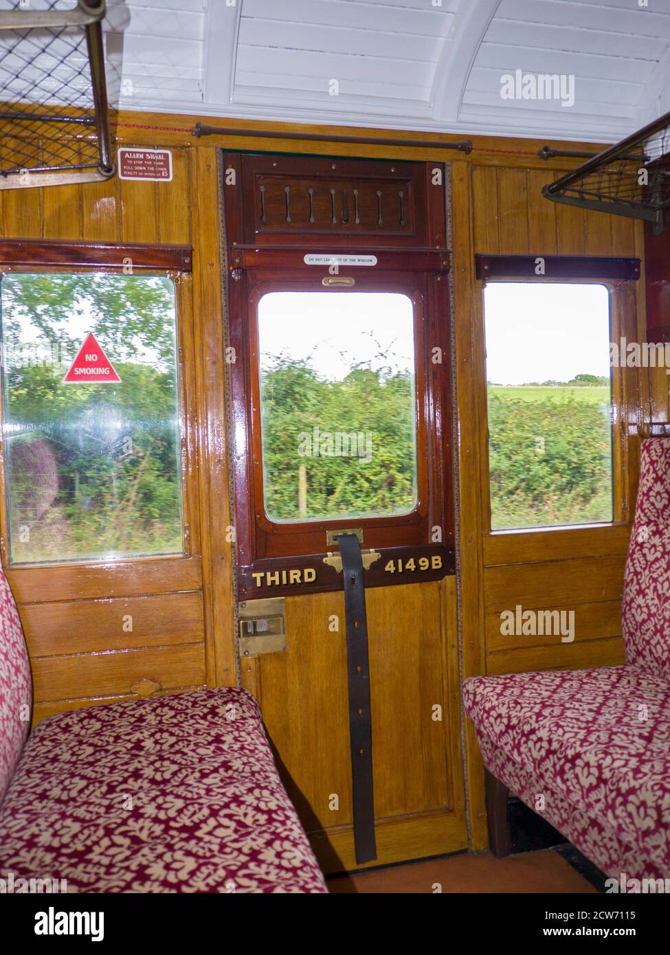 Historic railway carriage interior with polished wood paneling and drop ...