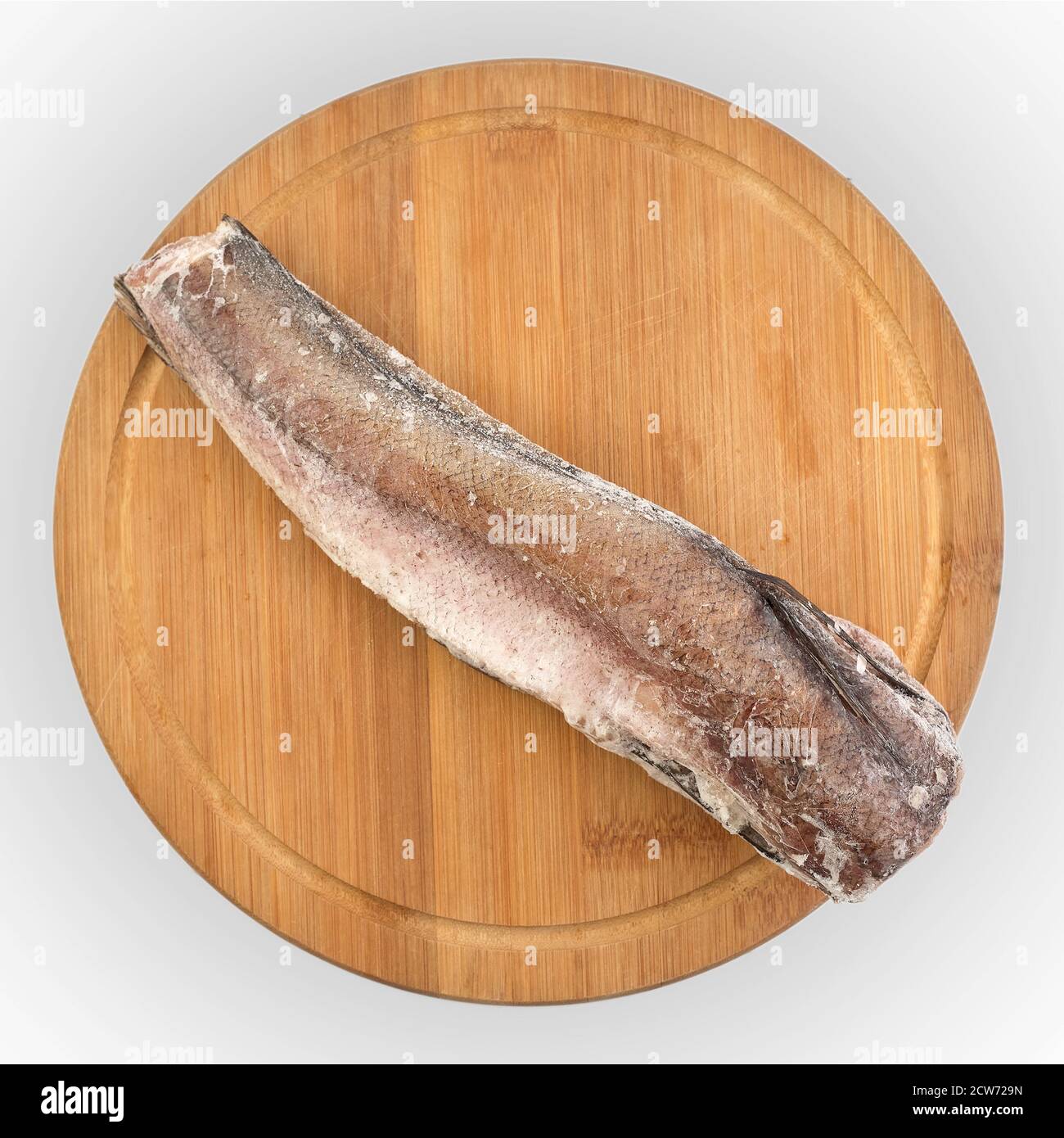 Frozen hake fish lies on the board, isolated on white background. Top ...