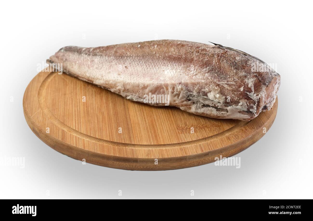 Frozen hake fish lies on the board, isolated on white background. Side ...