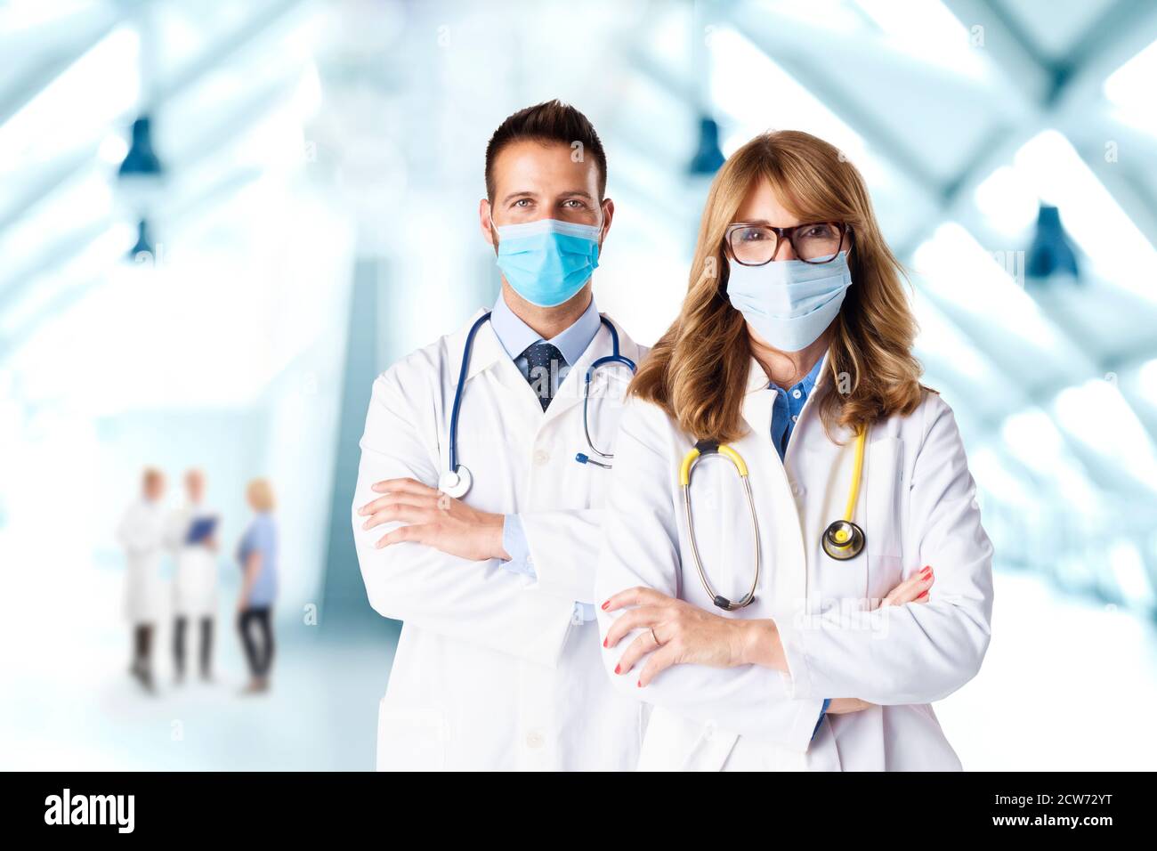 Shot of female and male doctors wearing face masks while standing ...
