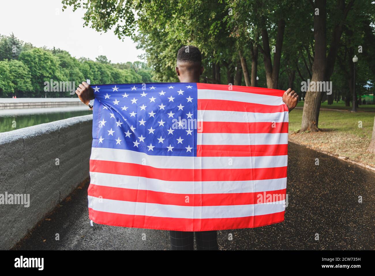 Black african-american man holding USA flag from his back walking ...
