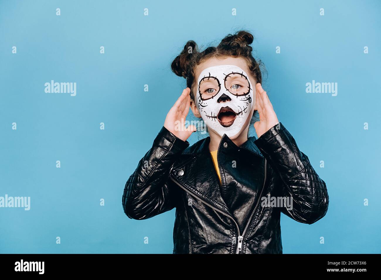 Stunned overjoyed little girl with bright scary makeup screams with ...