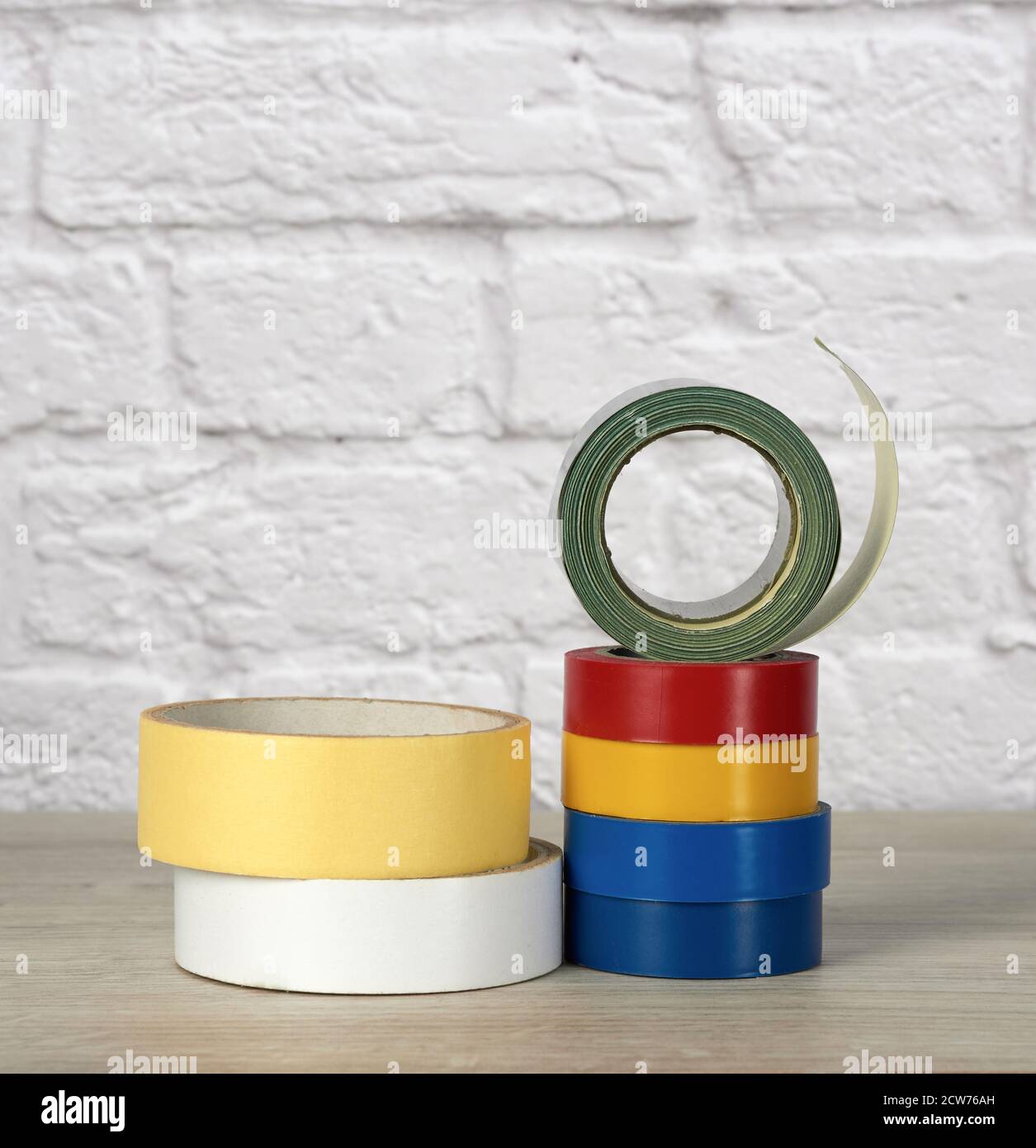 stack of colorful insulating tape on white brick wall background, close ...