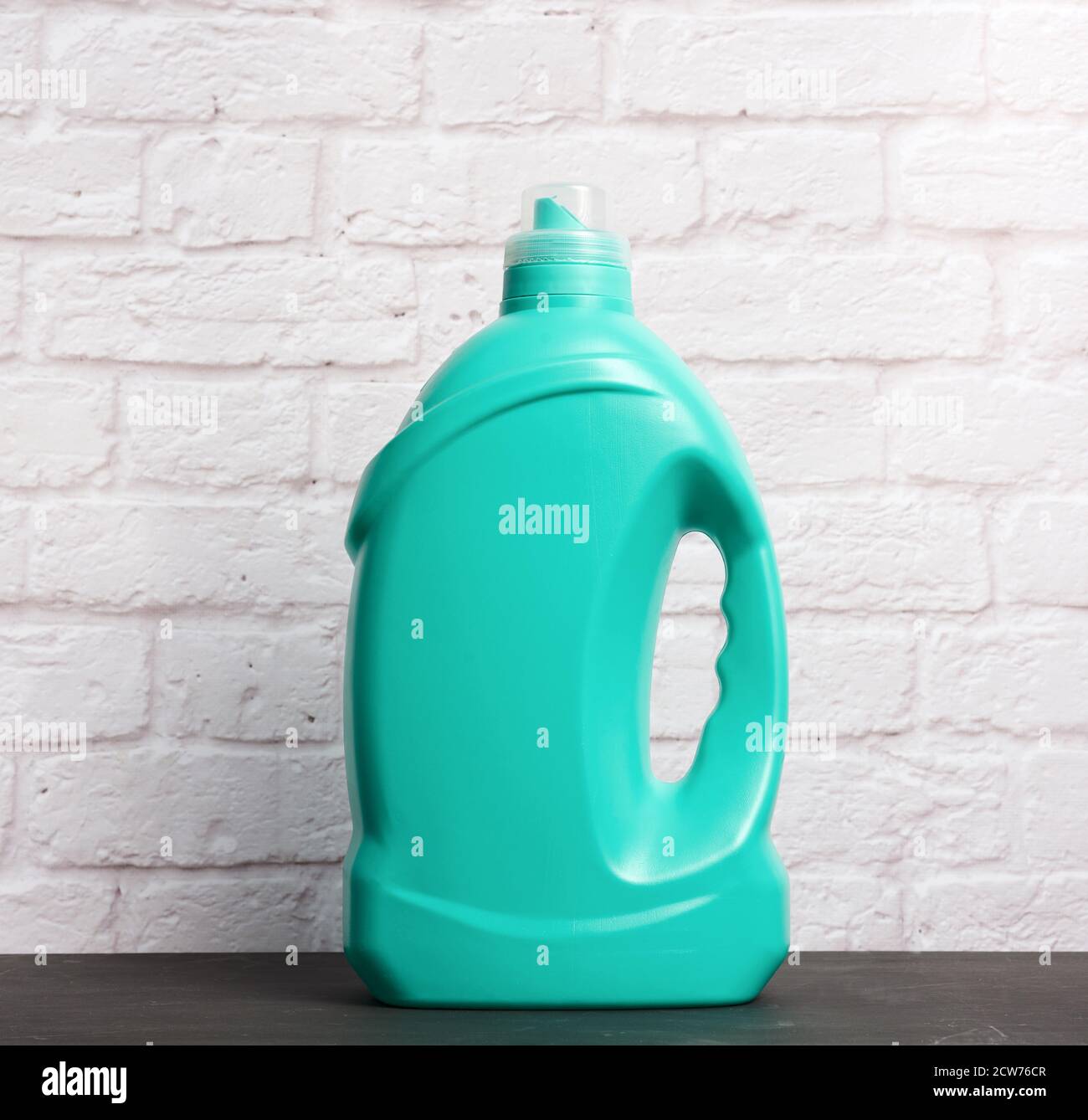 large plastic bottle with liquid detergent on white brick wall ...