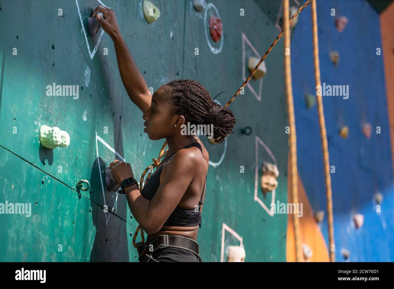 Young black woman climbing on training climbing wall. African climber ...