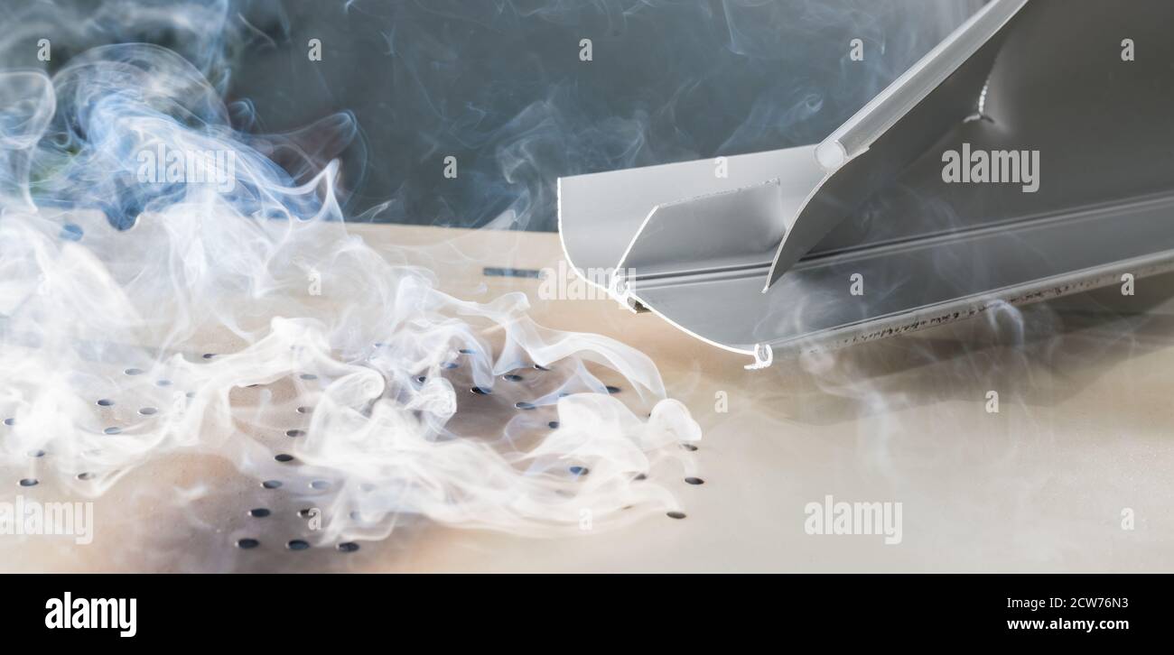White smoke escaping through sheet metal grid of hot smoldering ...