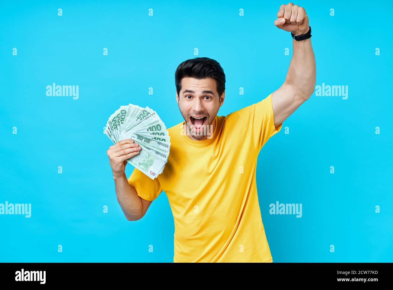 Happy excited man holding stack of money on blue background. Business ...
