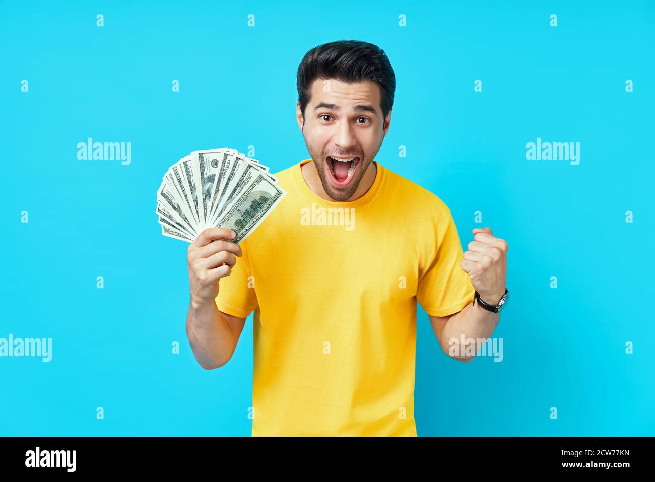 Happy excited man showing money banknotes on blue background. Business ...