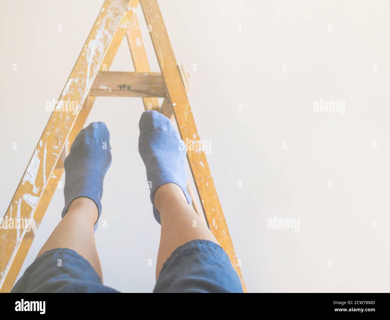 Woman with raised feet against wall with ladder Stock Photo - Alamy