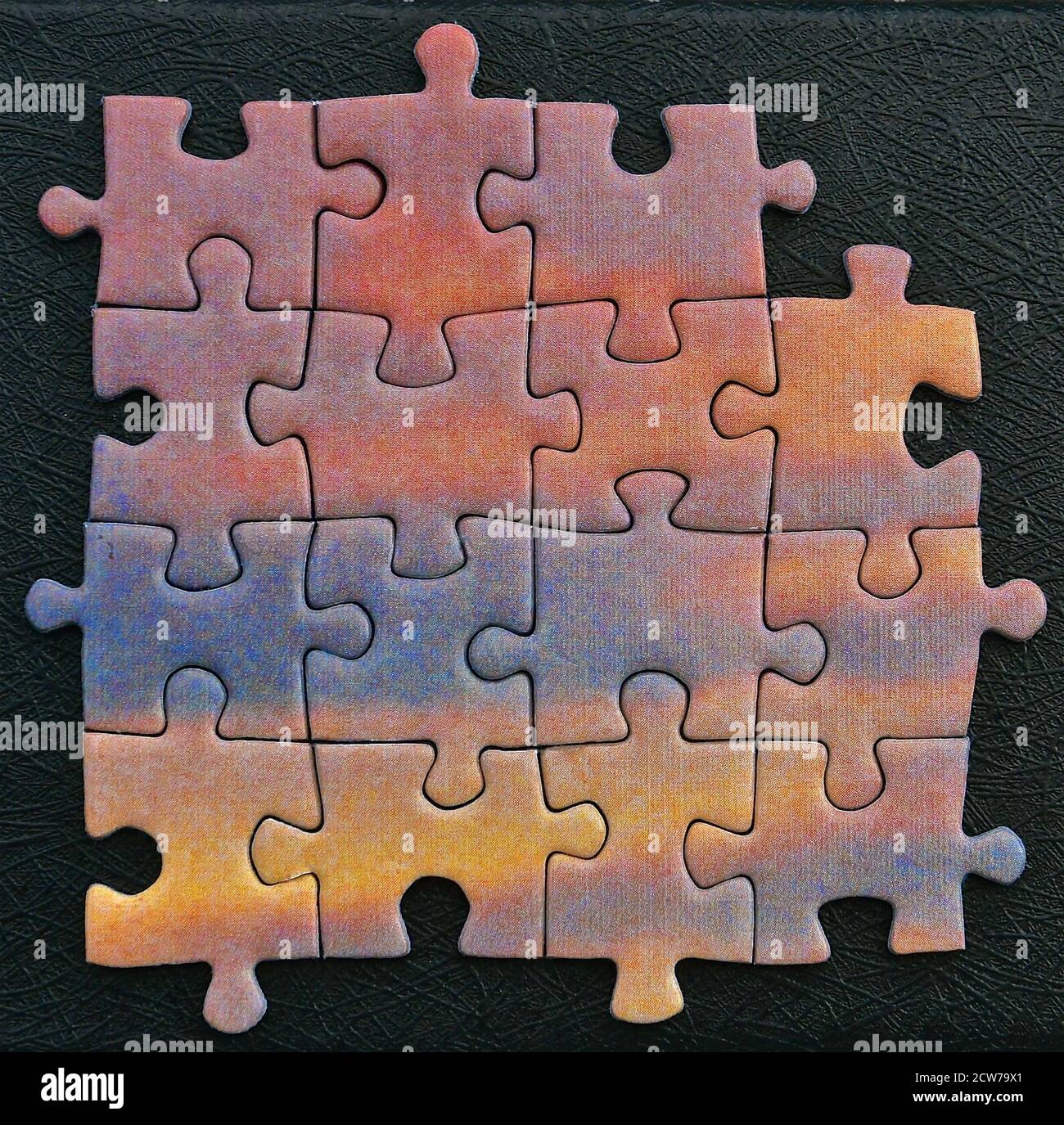 A square of colourful jigsaw pieces isolated on a black textured ...
