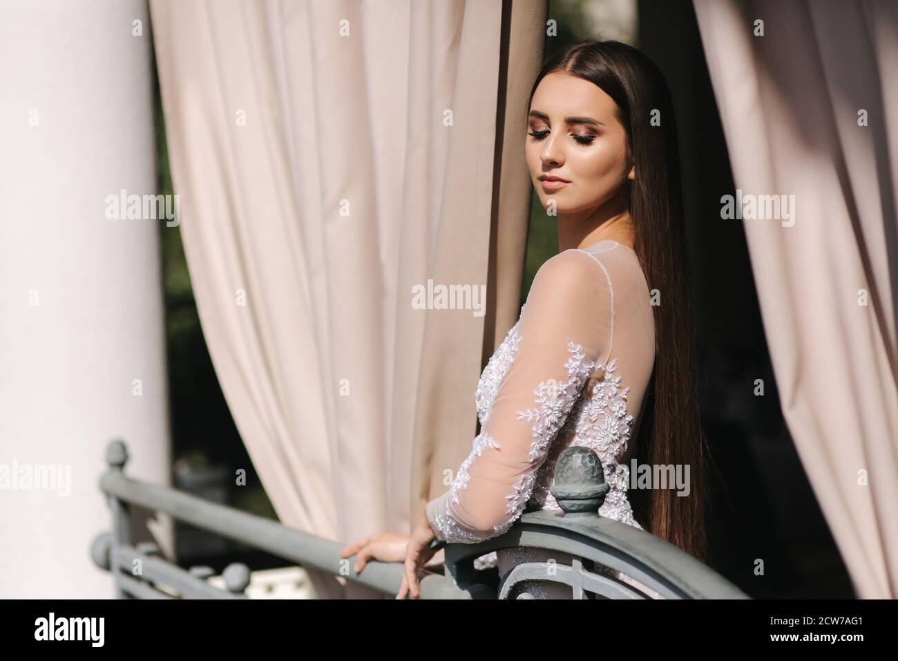 Beautiful young model in evening drees posing to photographer by the ...