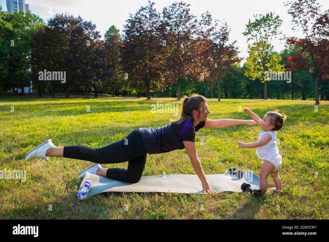 Young mother with her child do sports in the park. Little girl have fun ...