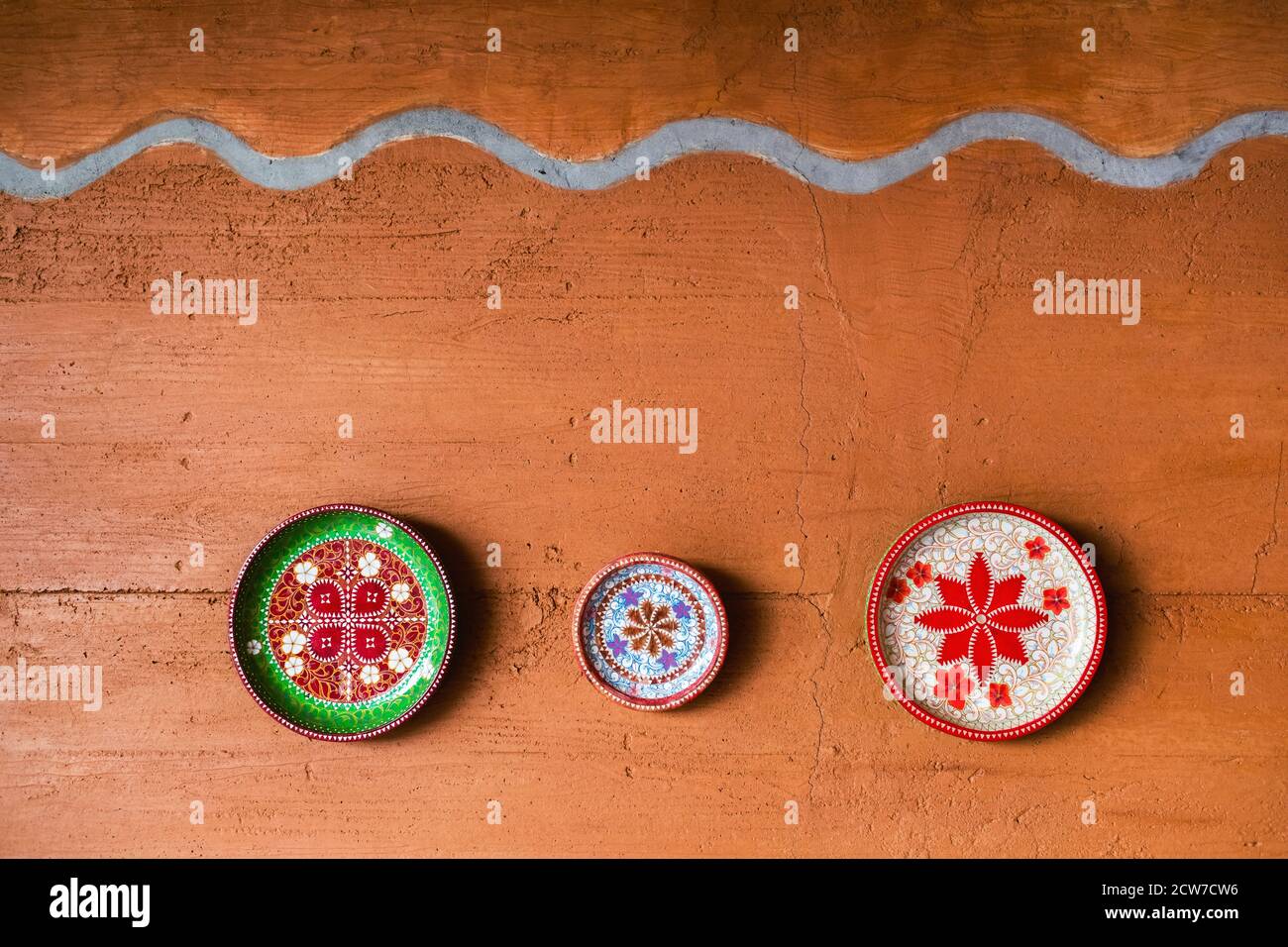 Red terracotta color clay wall with handmade souvenir plates as ...
