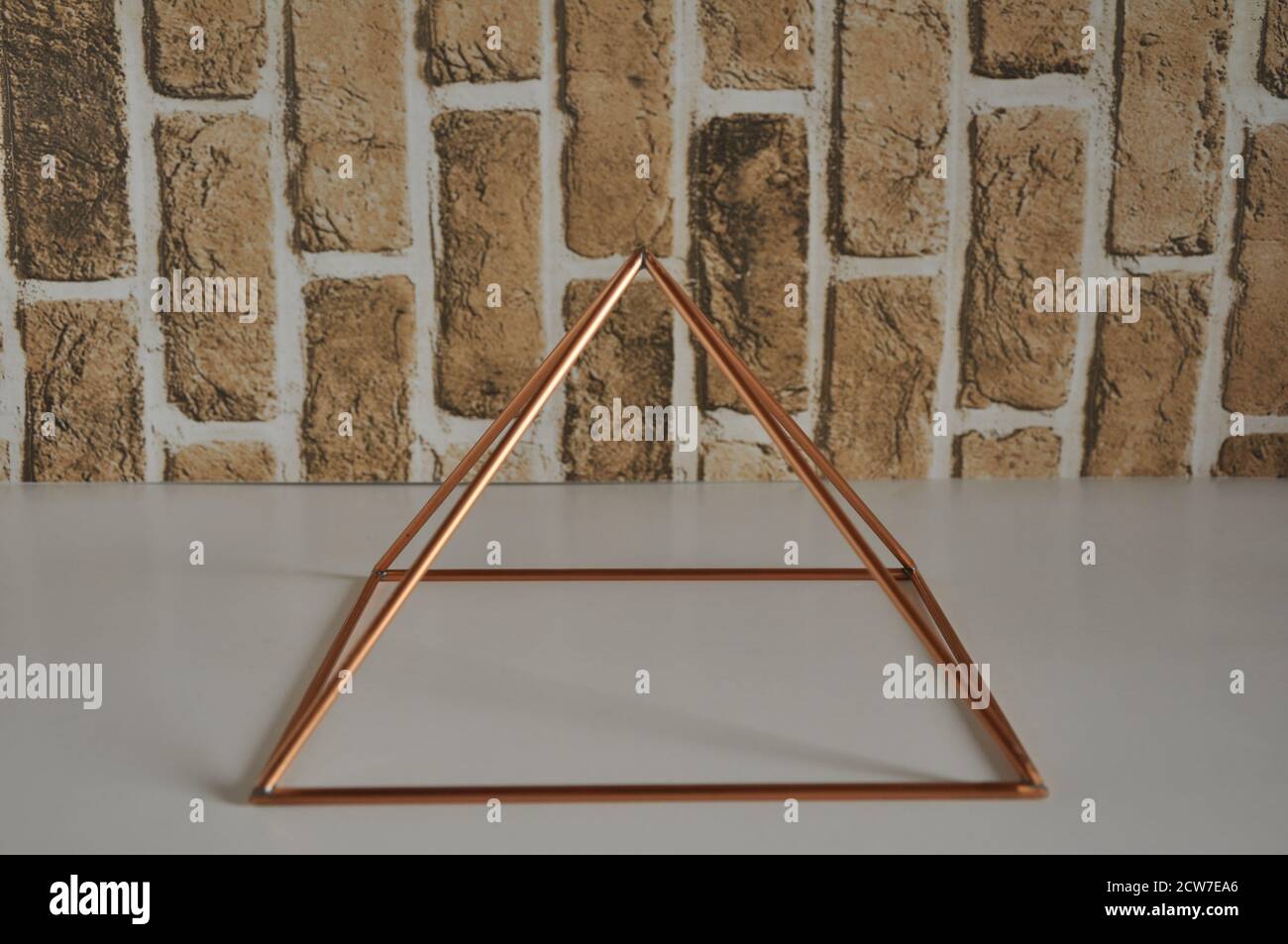 Copper pyramid, pyramid on white table, copper pyramid with stone wall ...