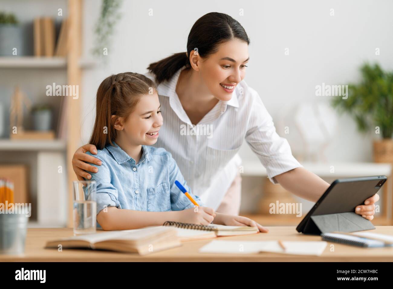 Back to school. Happy child and adult are sitting at desk. Girl doing ...