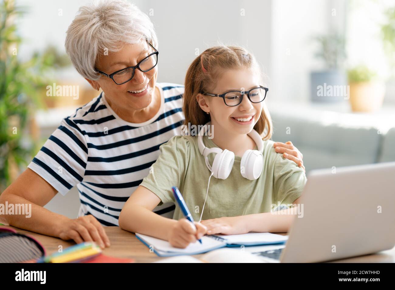Back to school. Happy child and adult are sitting at desk. Girl doing ...