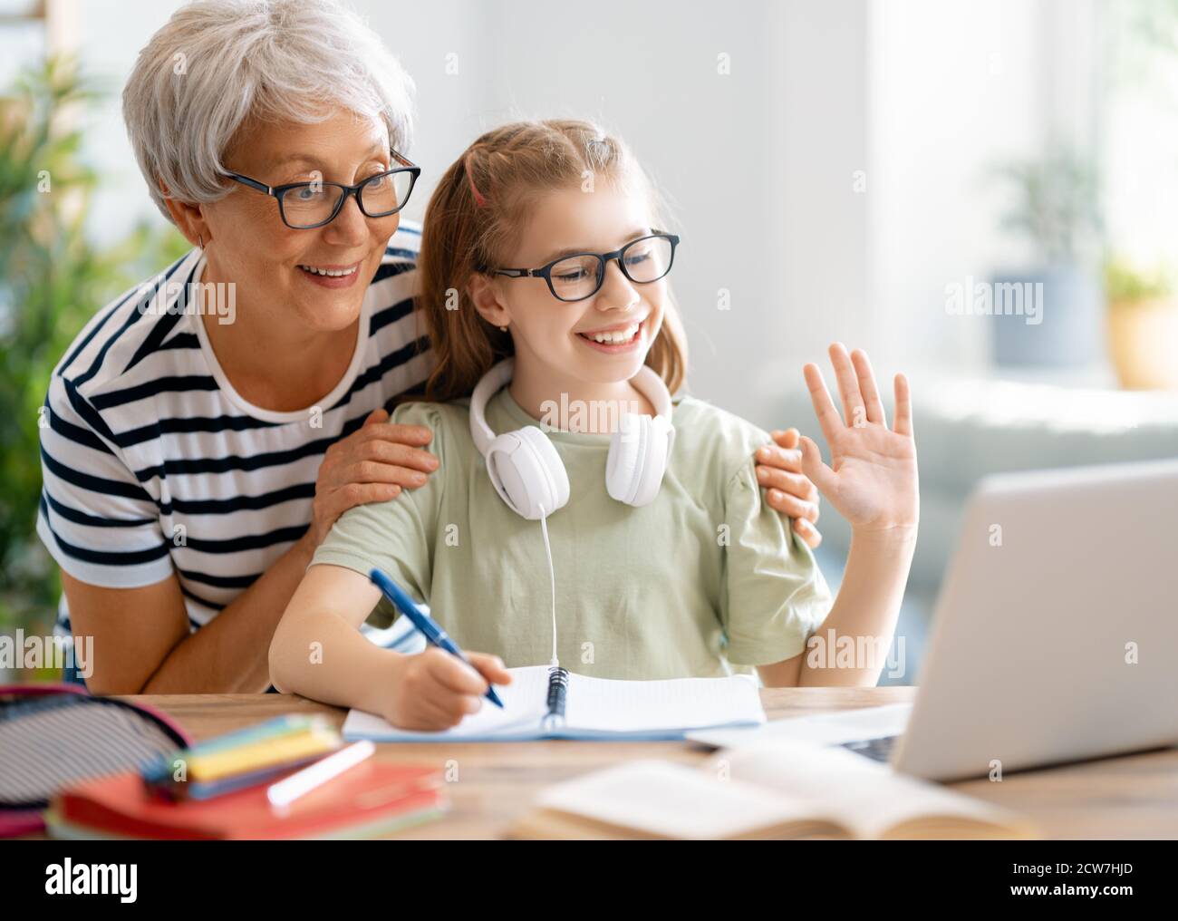Back to school. Happy child and adult are sitting at desk. Girl doing ...