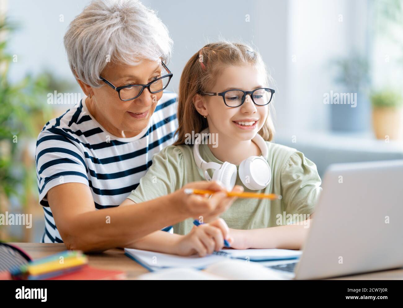 Back to school. Happy child and adult are sitting at desk. Girl doing ...