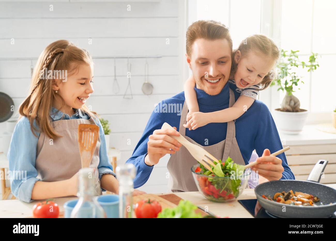 Healthy food at home. Happy family in the kitchen. Father and children ...