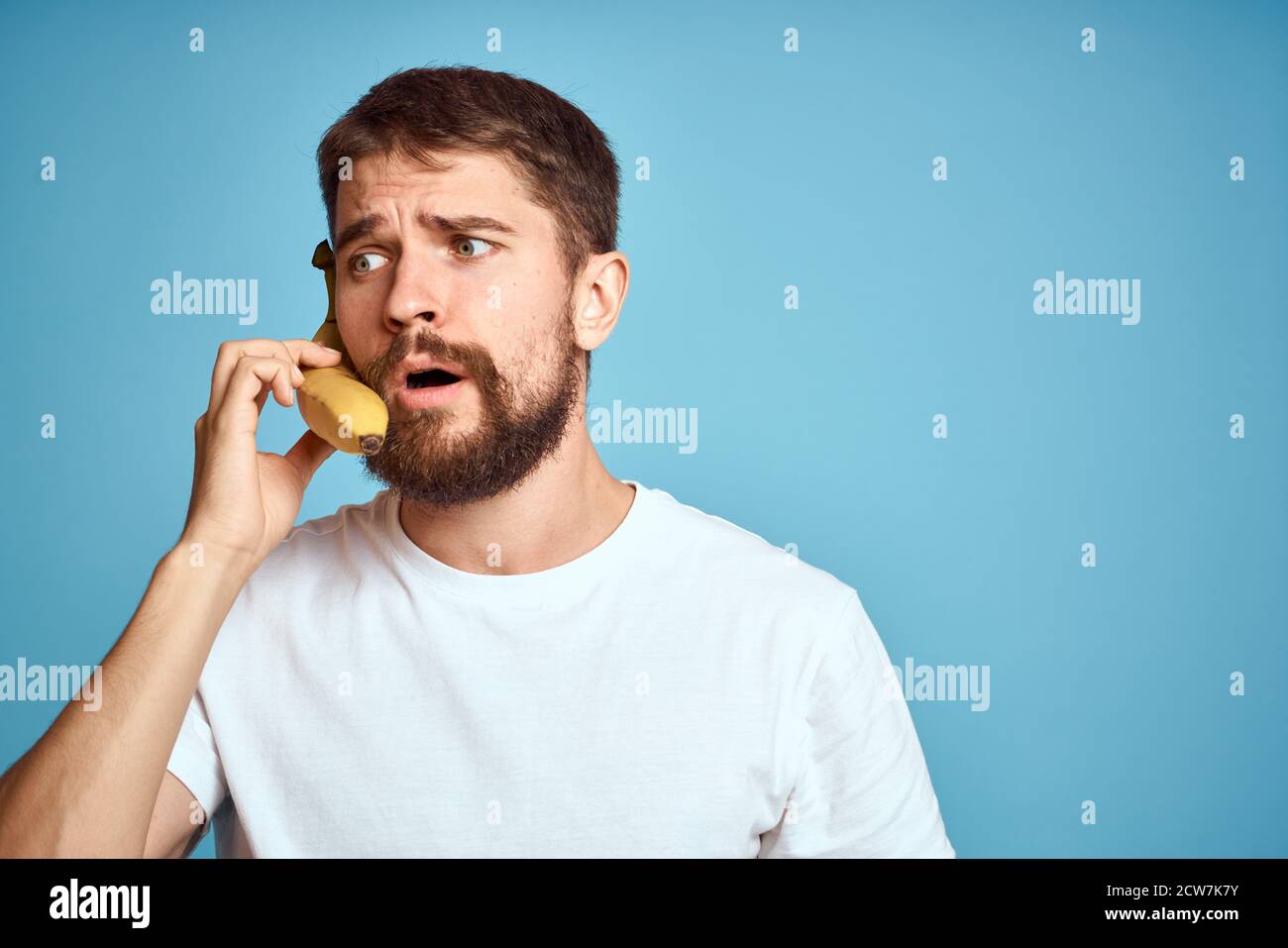 a man with a banana is caught in a white t-shirt on a blue background ...