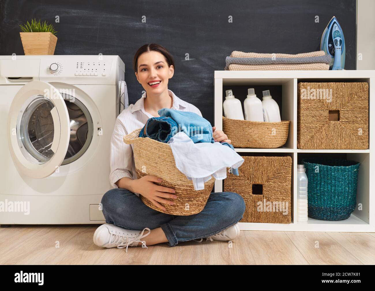 Beautiful young woman is smiling while doing laundry at home Stock ...