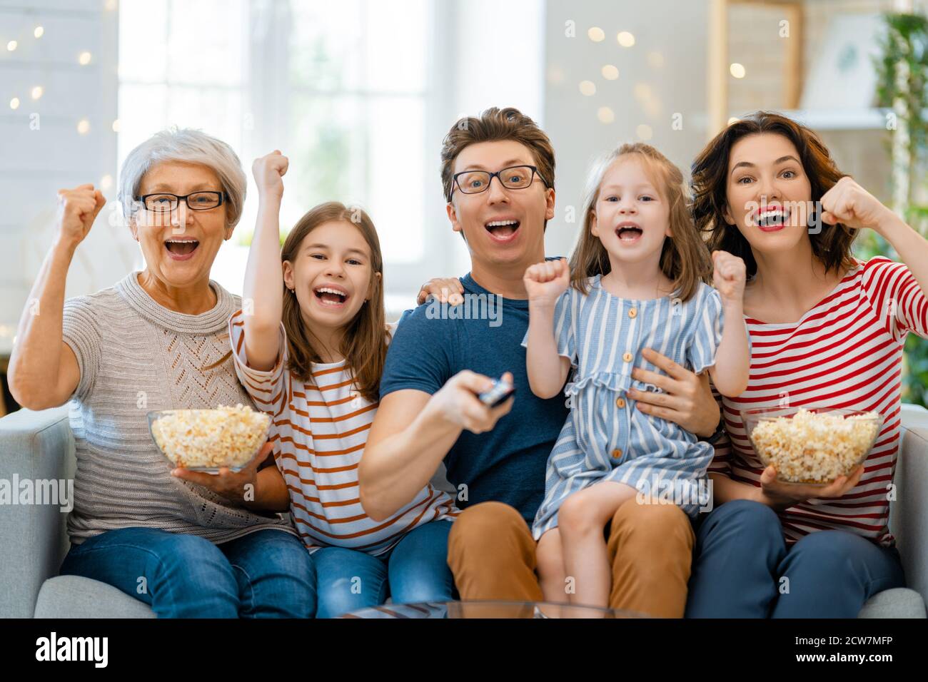 Happy family watching projector, TV, movies with popcorn at home ...
