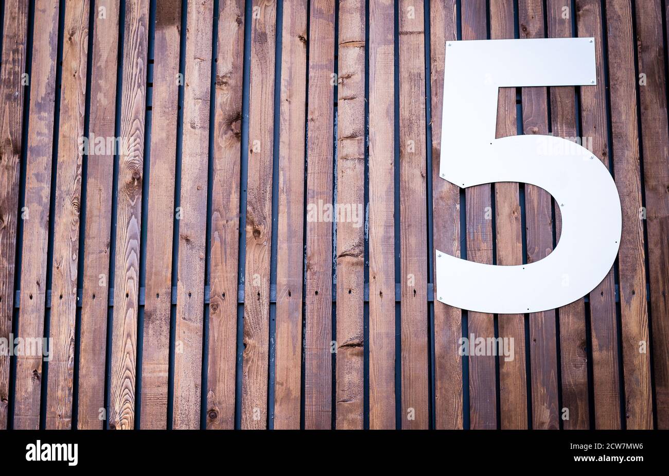 A large white number "five" on the wooden surface. Background of narrow ...