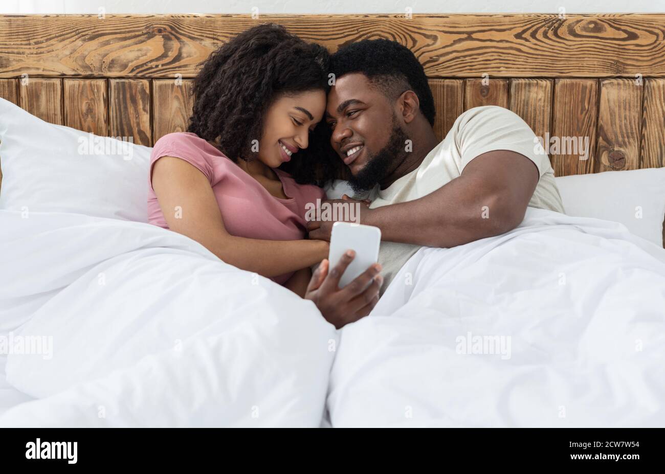 Emotional couple cuddling and watching photos together on smartphone ...