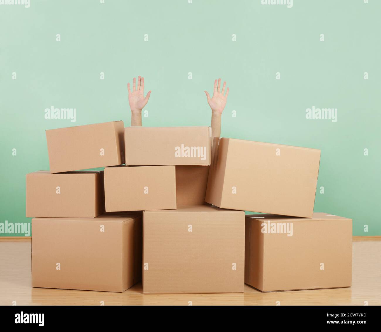 Hands raised behind cardboard boxes Stock Photo - Alamy