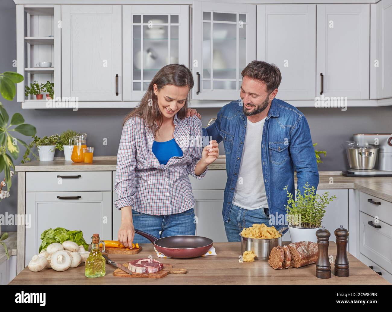 Happily married couple cooking together in the kitchen Stock Photo - Alamy