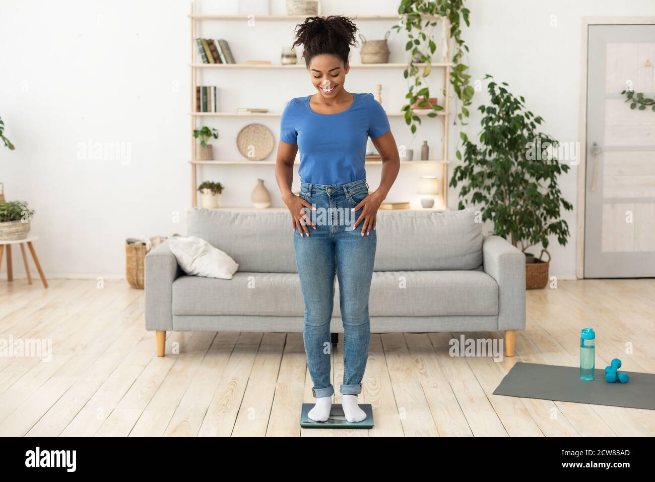 Smiling African Woman Weighing Herself On Scales Posing At Home Stock ...