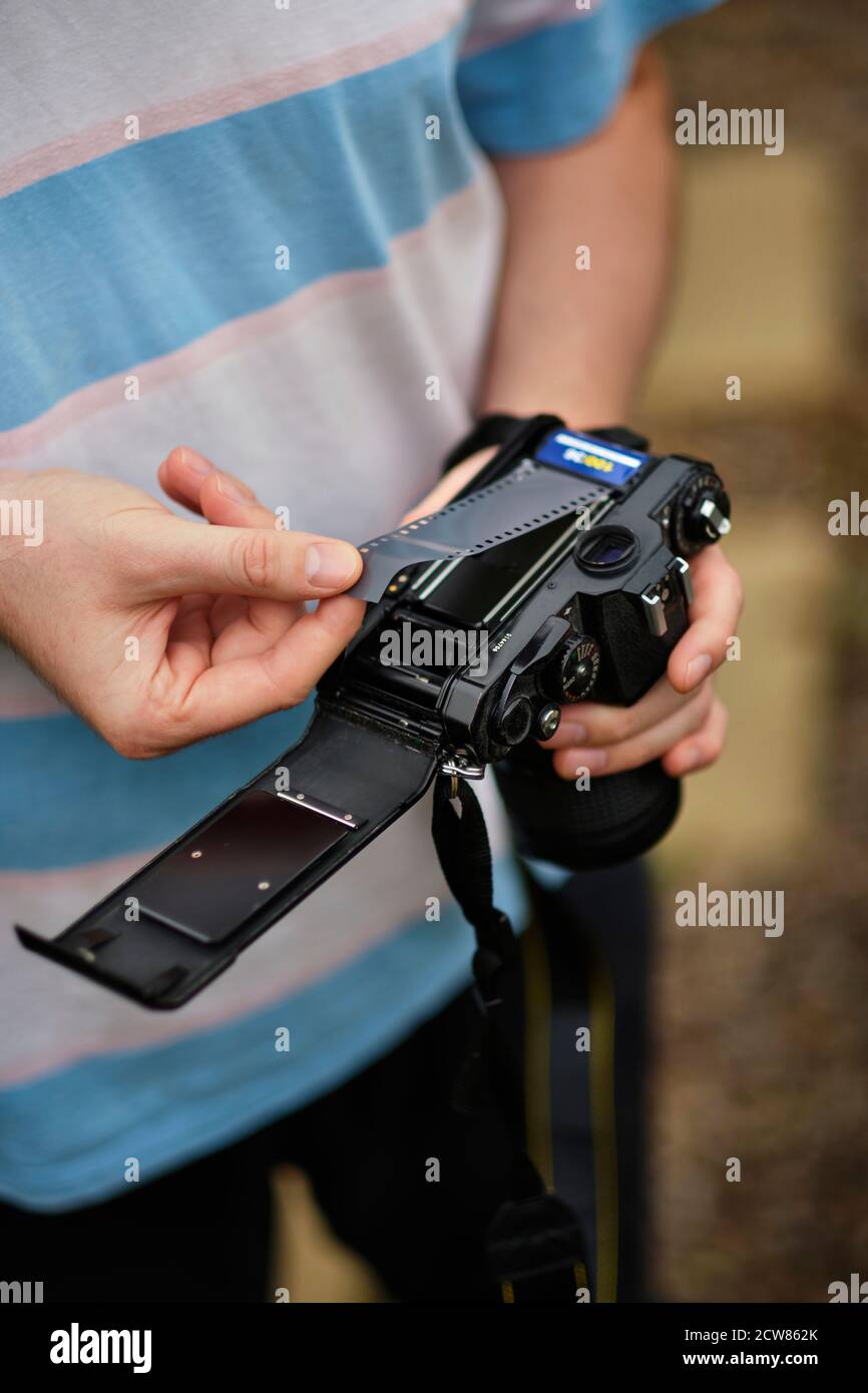 A young man loads photographic film into an analogue camera, a medium ...