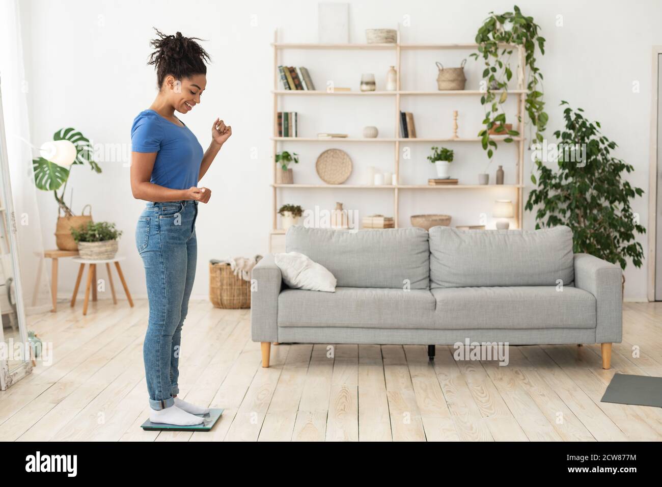Excited Black Lady Weighing Standing On Weight Scales At Home Stock ...
