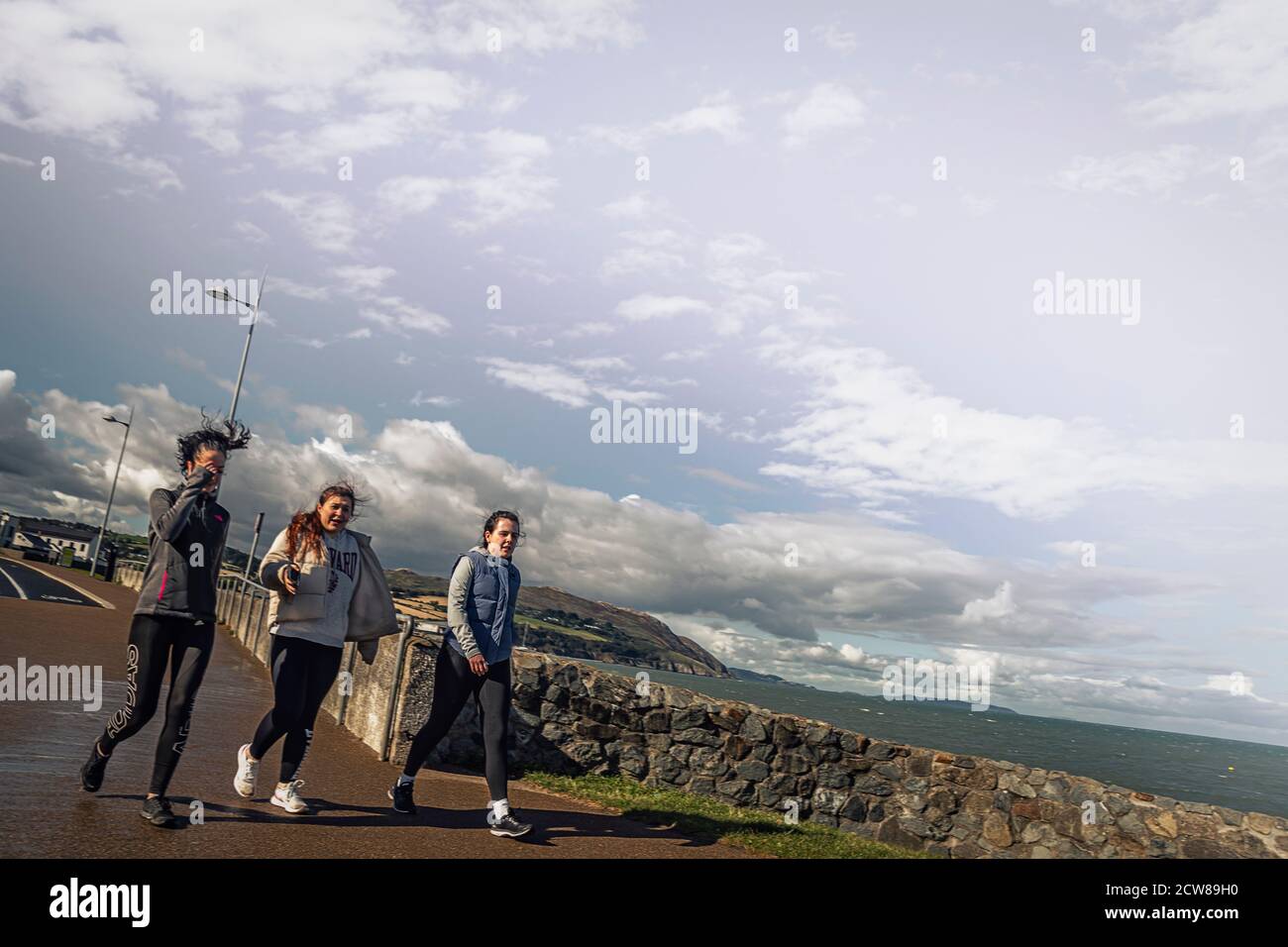 Everyday life. Three young ladies in sport wearing walking at sea broad ...