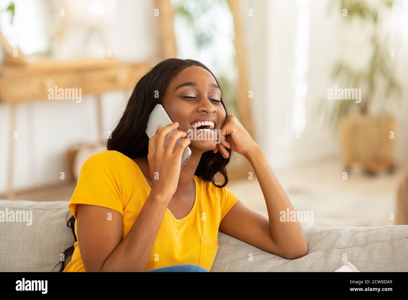 Portrait of positive African American lady making call on mobile phone ...