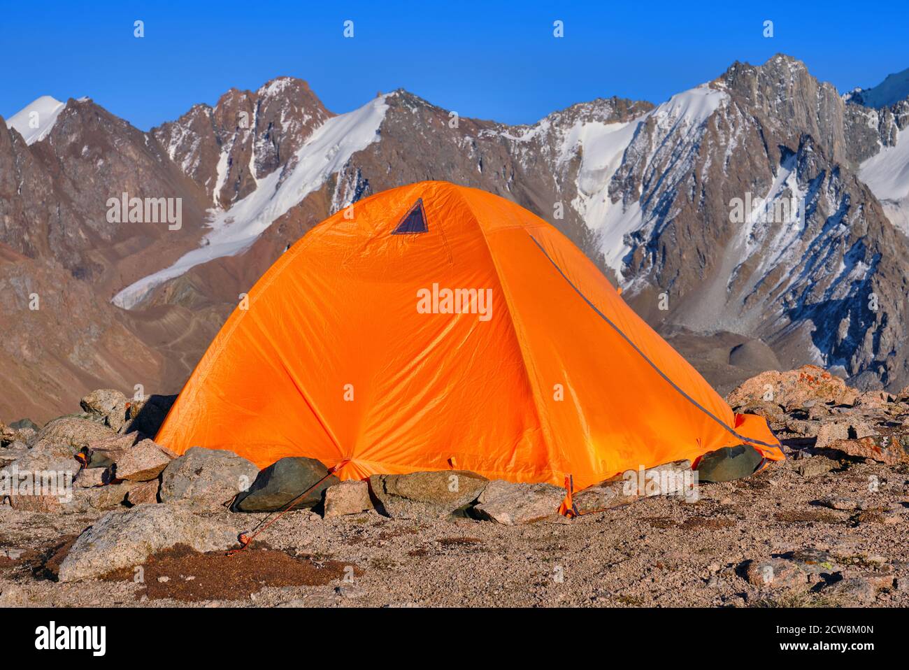 Tent is placed on a mountain ridge and reinforced with stones around ...
