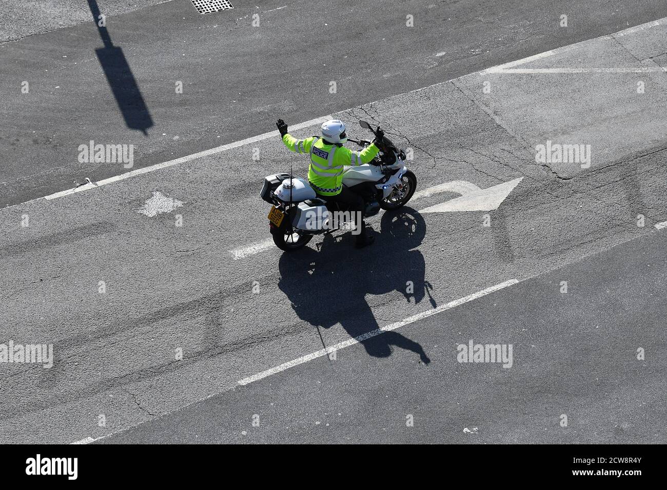A police motorcycle rider stops the traffic to allow a VIP to pass ...