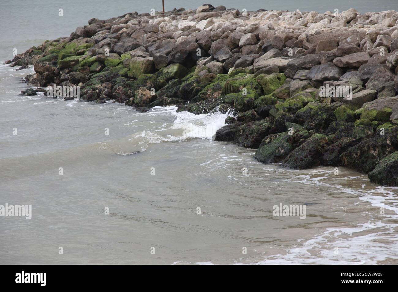 Waves lap against a stone and rock groyne, designed to stop coastal ...