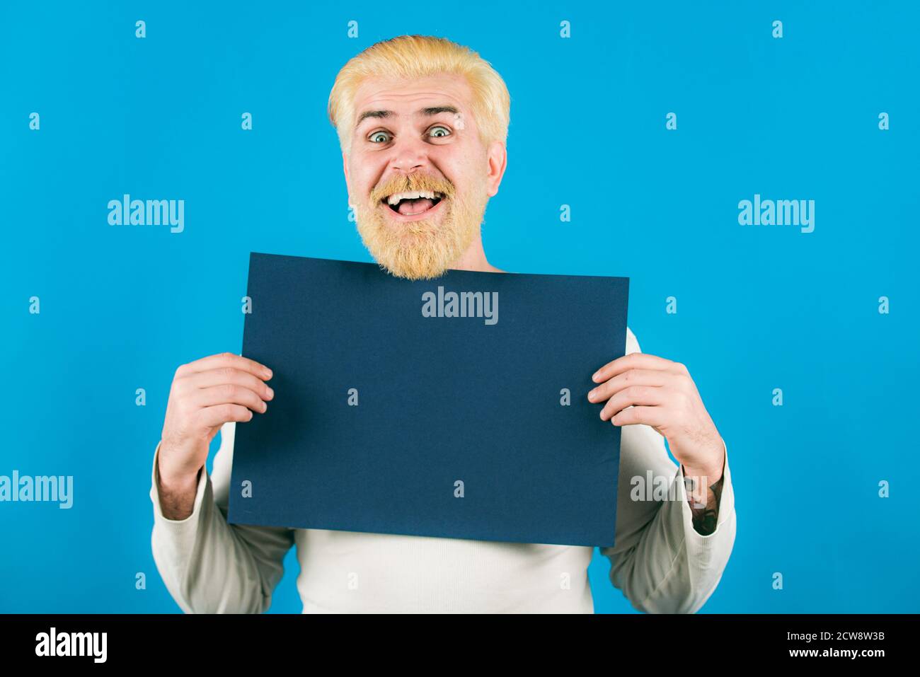 Young man shows a sheet of paper in the camera on a color background ...