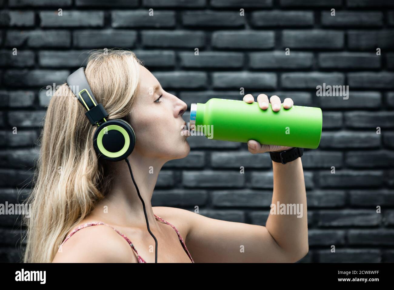 Young blond woman on black background drink fresh spring water from ...