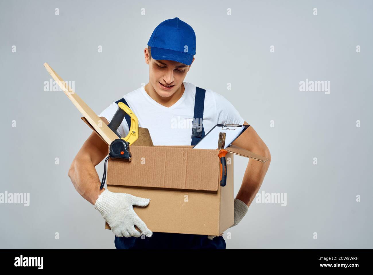 man in working uniform with a box in his hands tools loader delivery ...