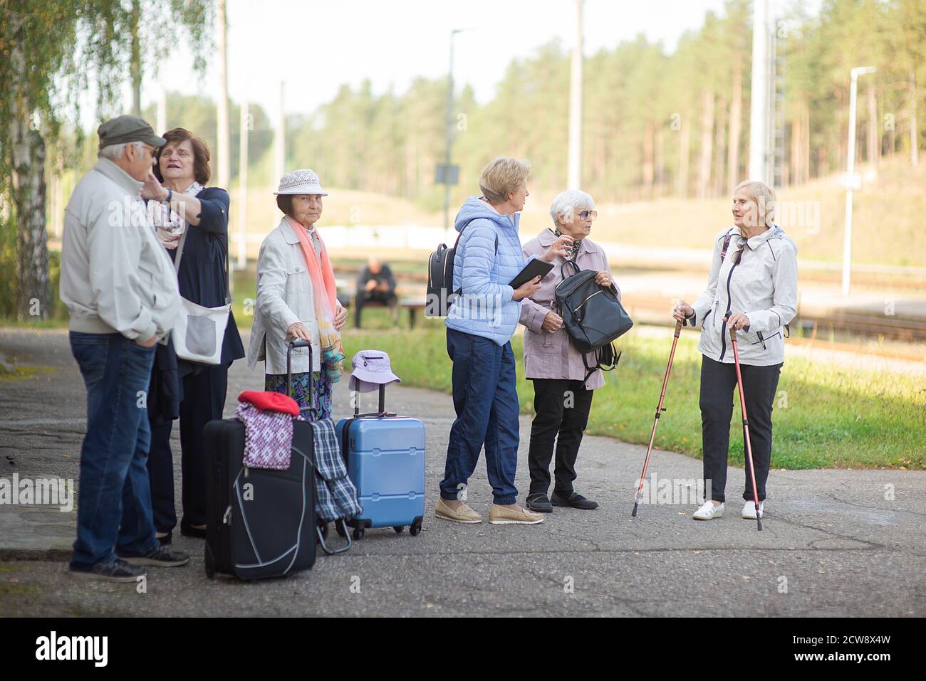A group of positive senior elderly people travelers waiting for train ...