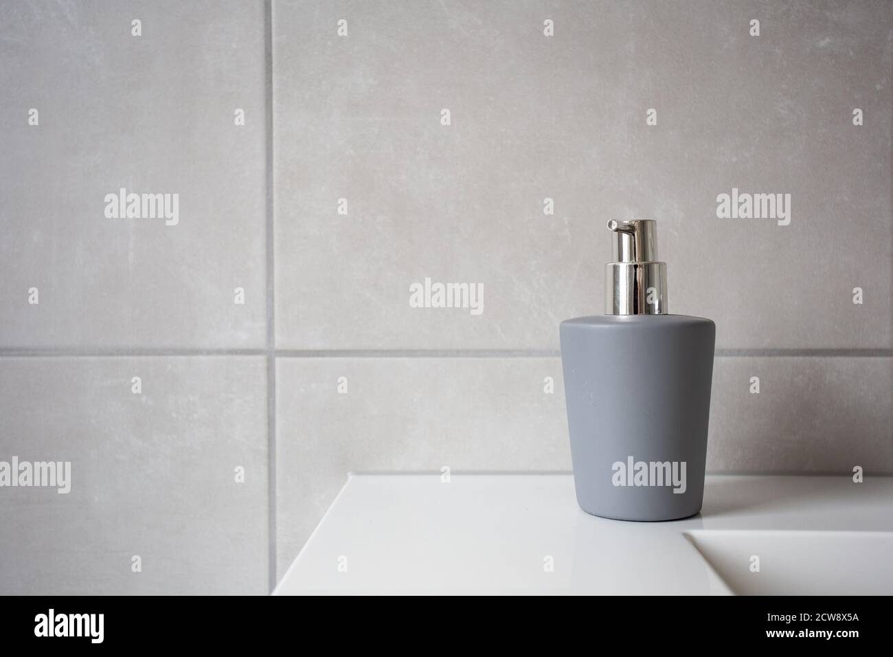 Gray soap dispenser for liquid soap, natural stone tiled bathroom ...