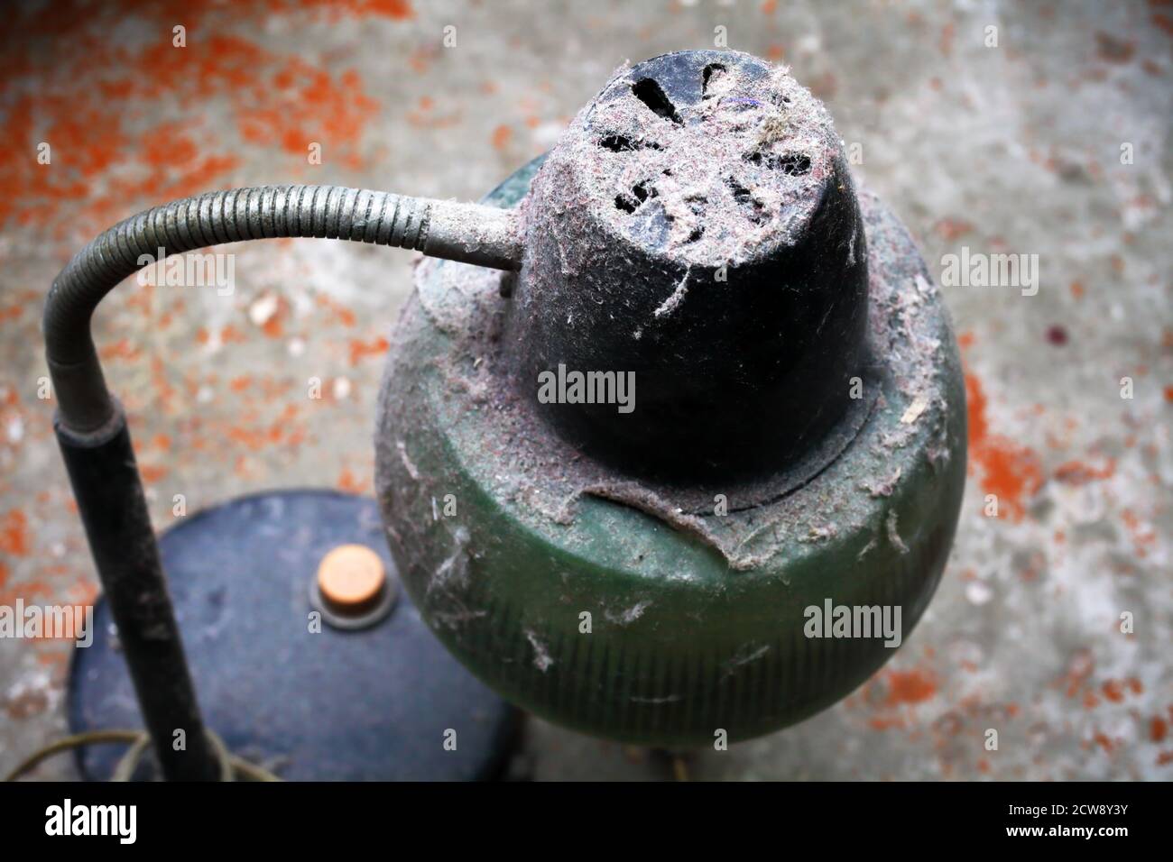 Old table lamp under a large layer of dust stands on a concrete floor ...