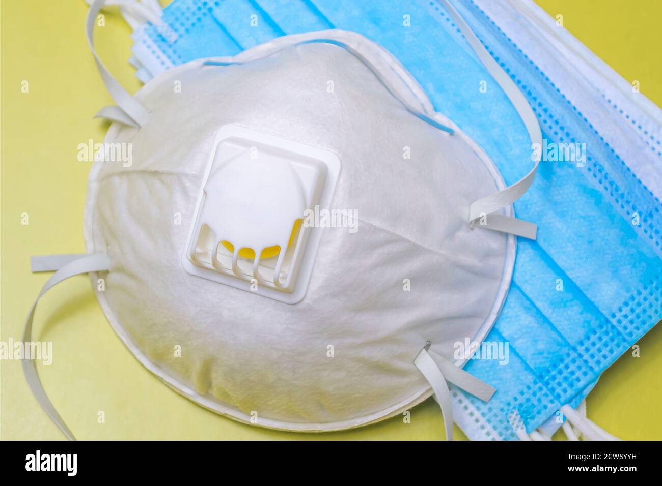 A mask with a protective filter and many medical masks on a yellow ...