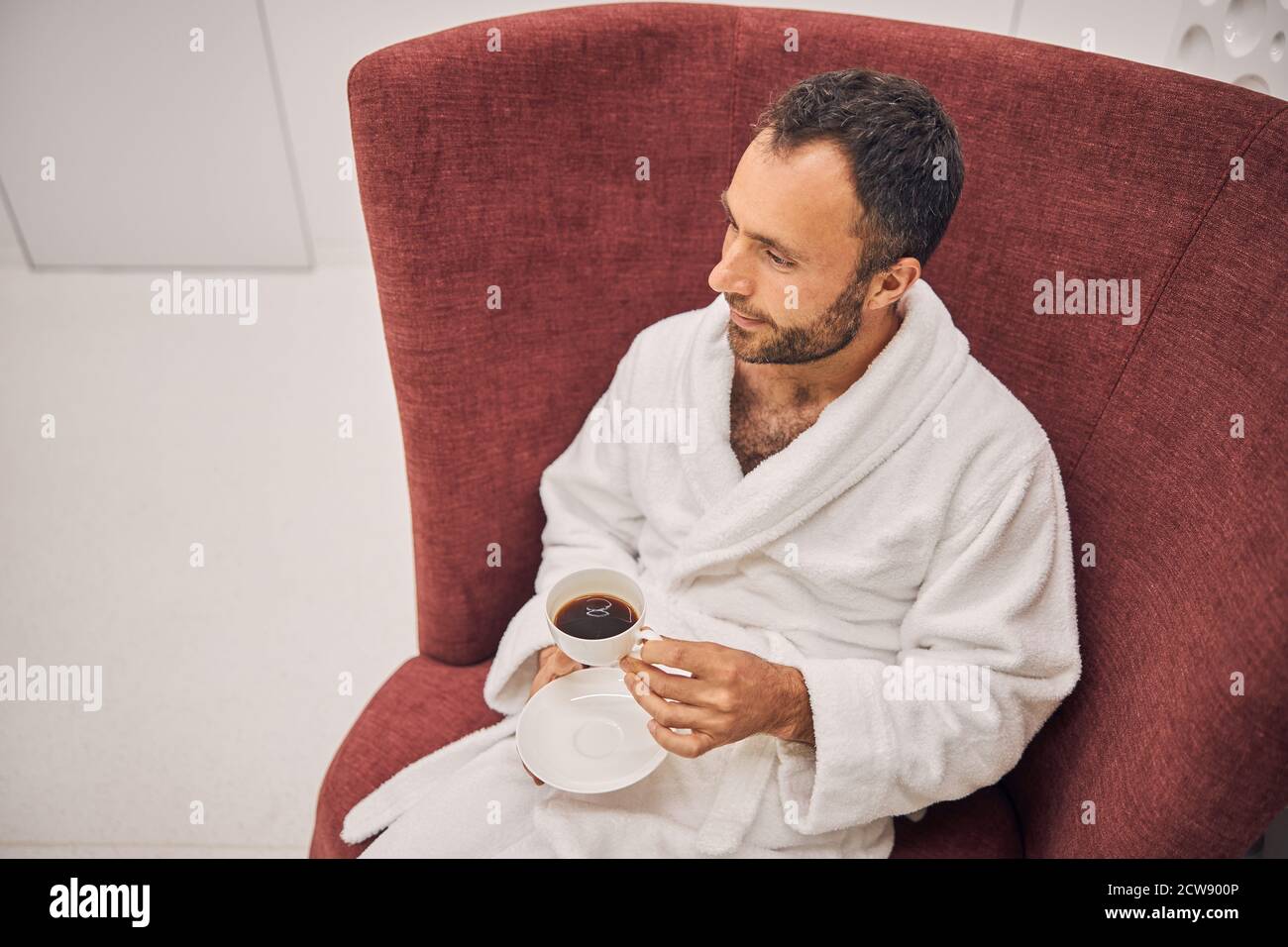 Handsome young man sitting in chair and drinking coffee Stock Photo - Alamy