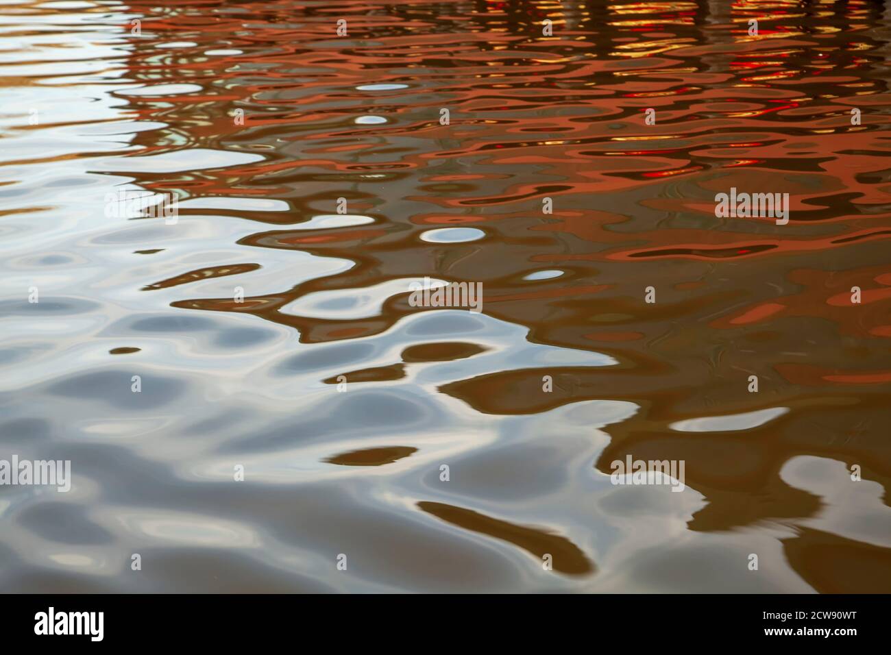 Surface of water reflecting colors.Water ripples and yellow reflections ...