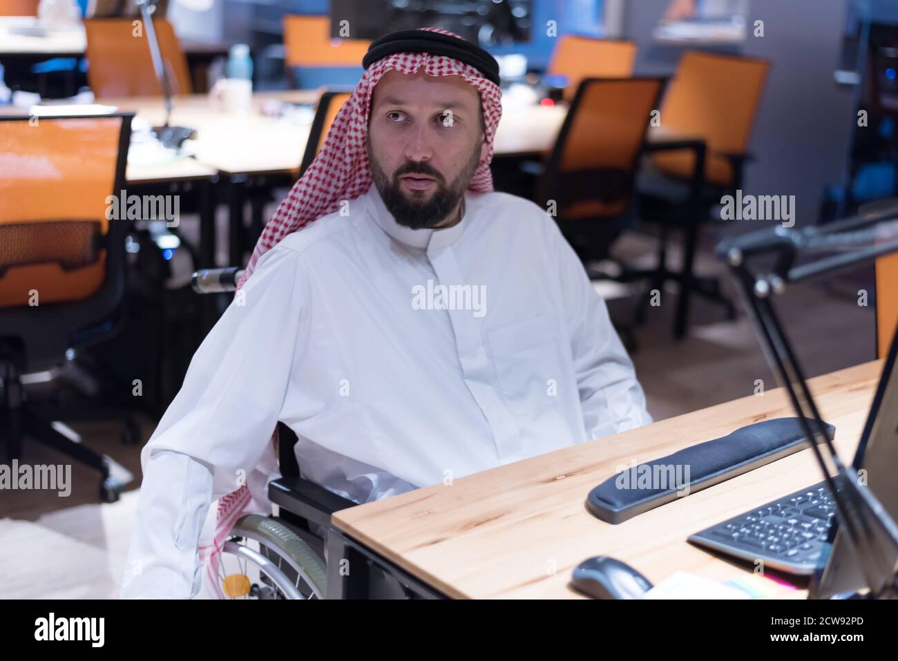 Handicapped Arabic businessman in tradition suit working in office ...