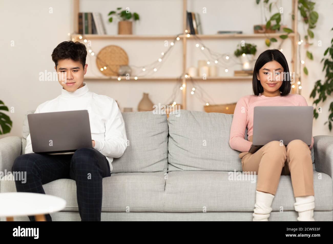 Korean Couple Using Laptop Computers Sitting On Couch At Home Stock ...