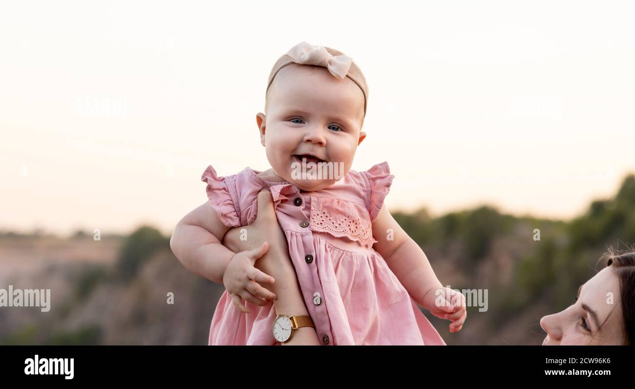 Laughing mother lifting her adorable baby daughter in air. Baby is ...